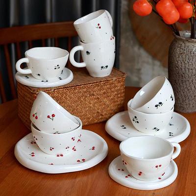 Cherry patterned ceramic tea cups, dessert bowls, and plates